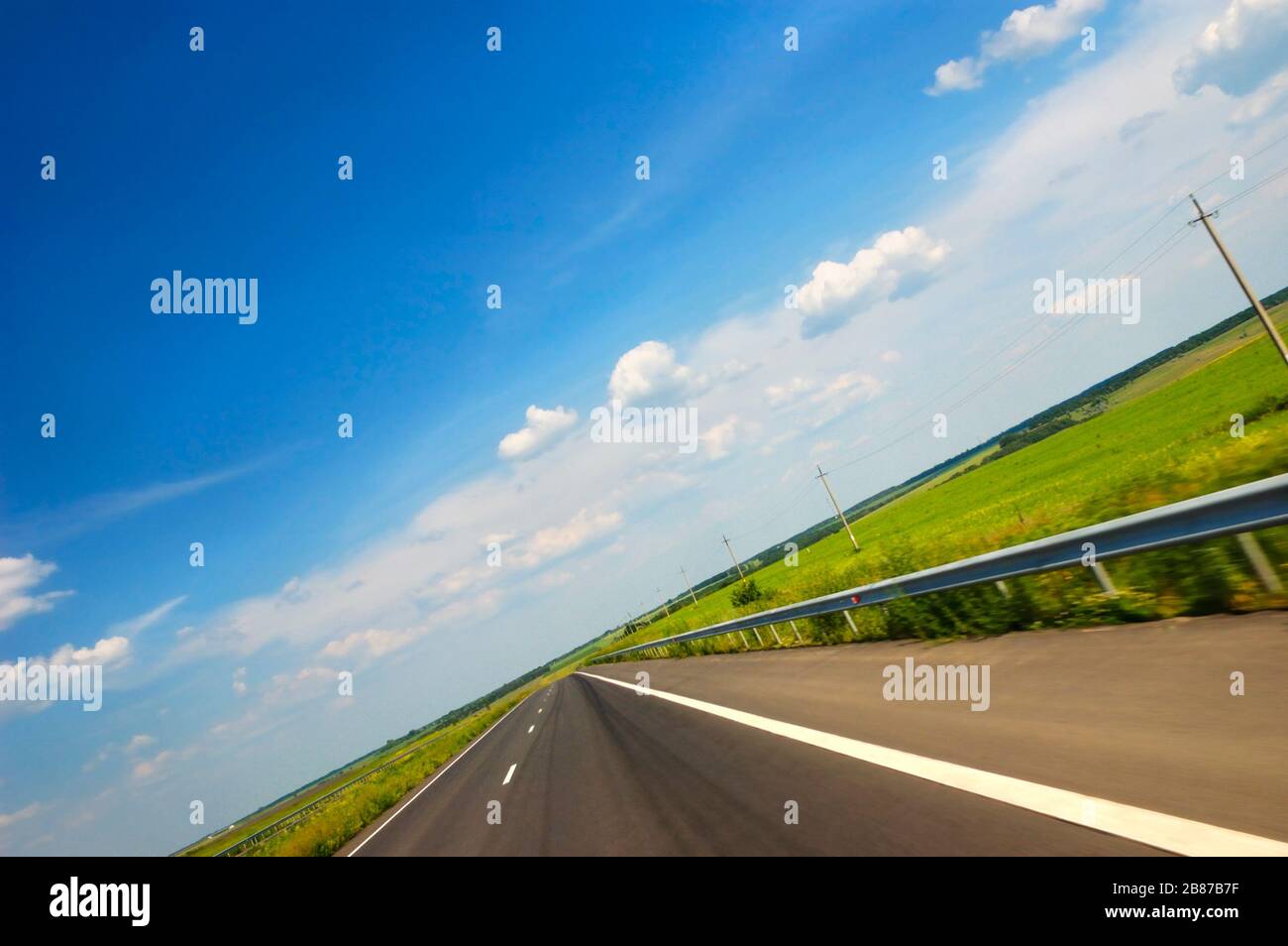Tilted angle shot is a smooth highway surrounded by beautiful summer ...