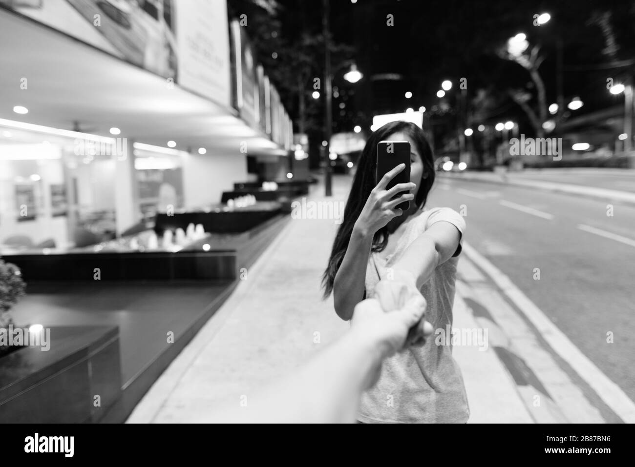 Young beautiful Asian woman wandering in the city streets at night ...