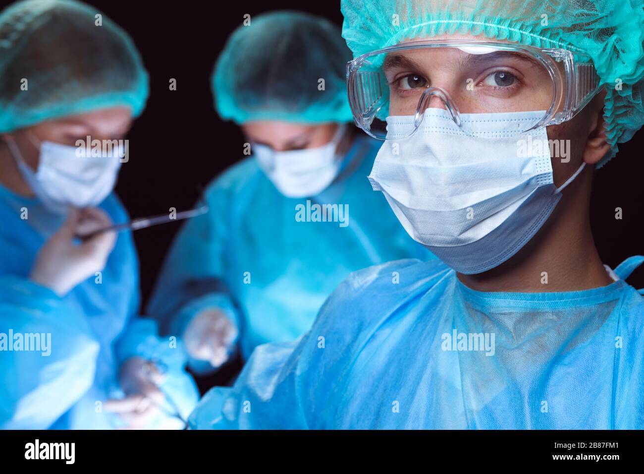 Group of surgeons wearing safety masks performing operation. Medicine ...