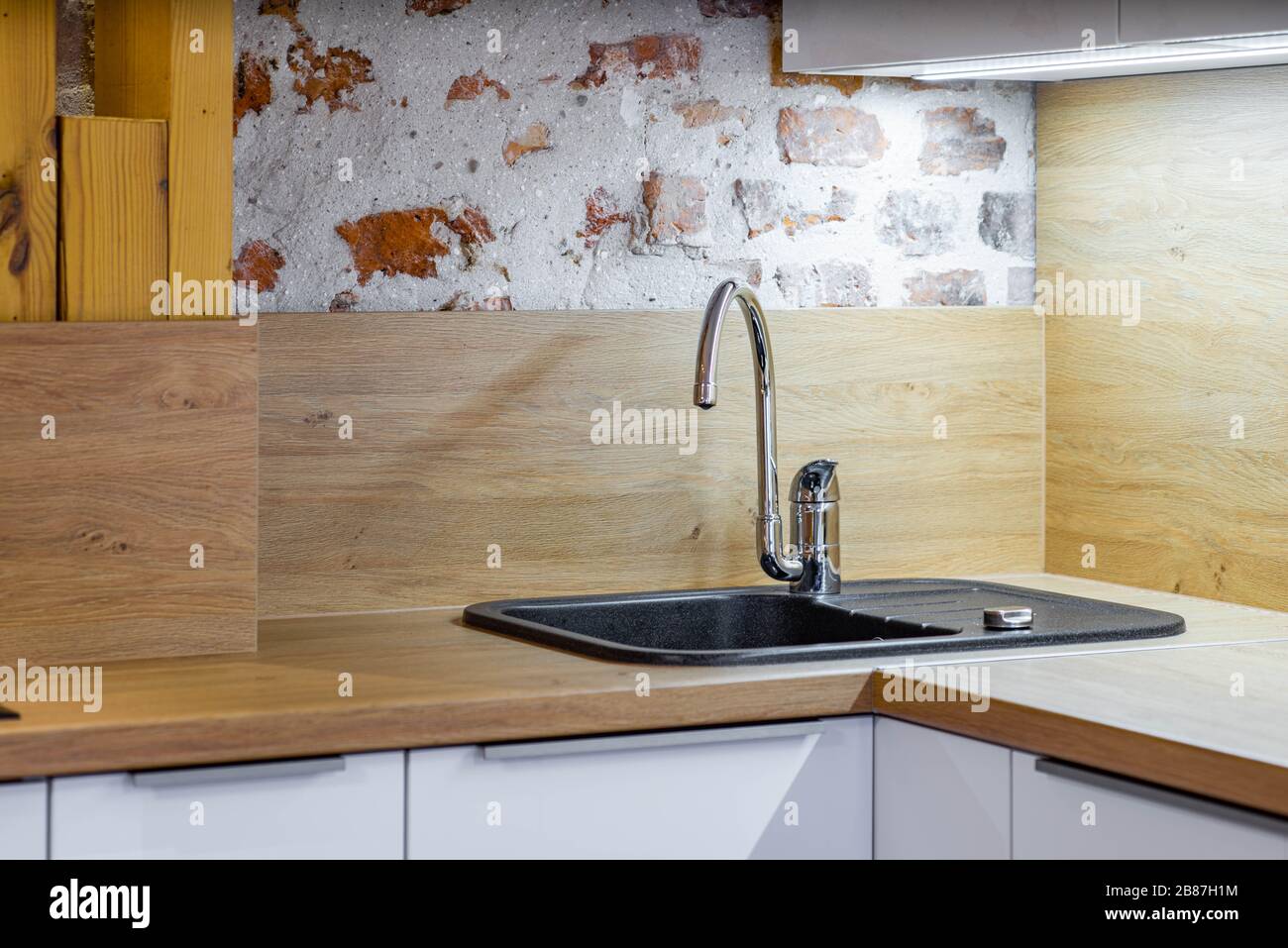 Modern loft interior of kicthen. Brick wall. Close-up of black sink ...