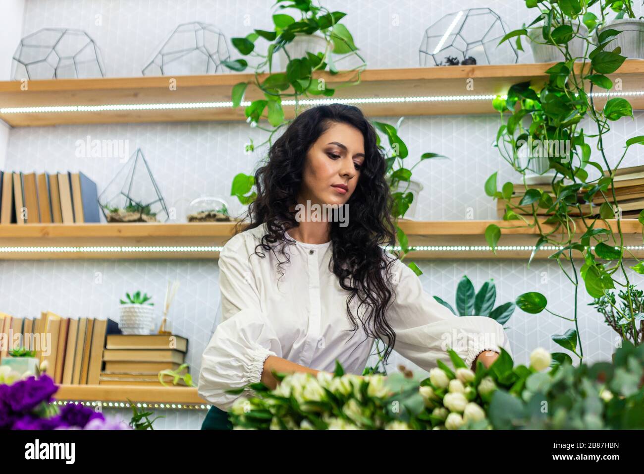Attractive young woman florist is working in a flower shop Stock Photo ...