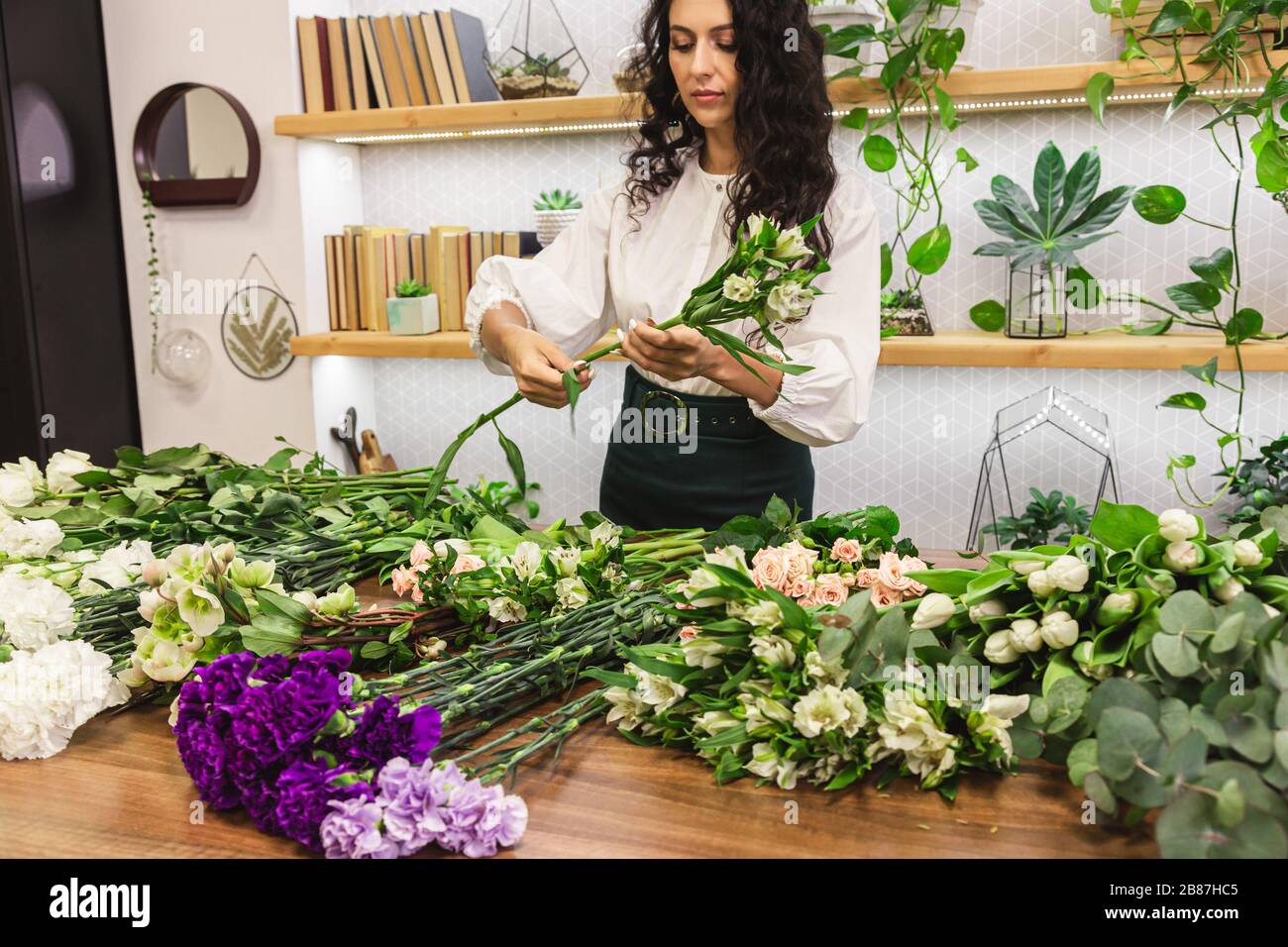 Attractive young woman florist is working in a flower shop Stock Photo ...