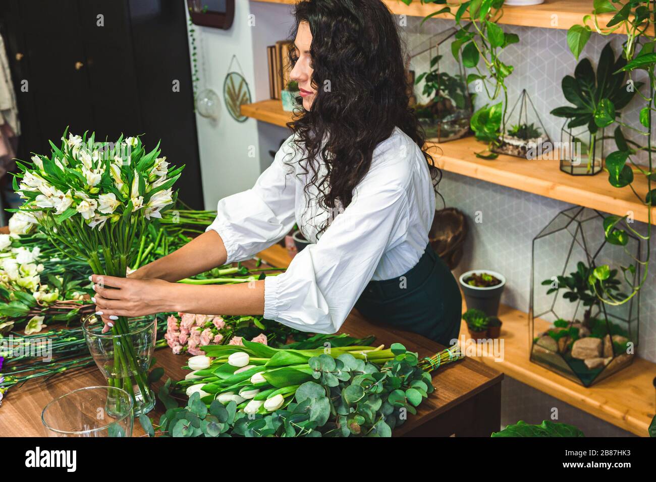 Attractive young woman florist is working in a flower shop Stock Photo ...
