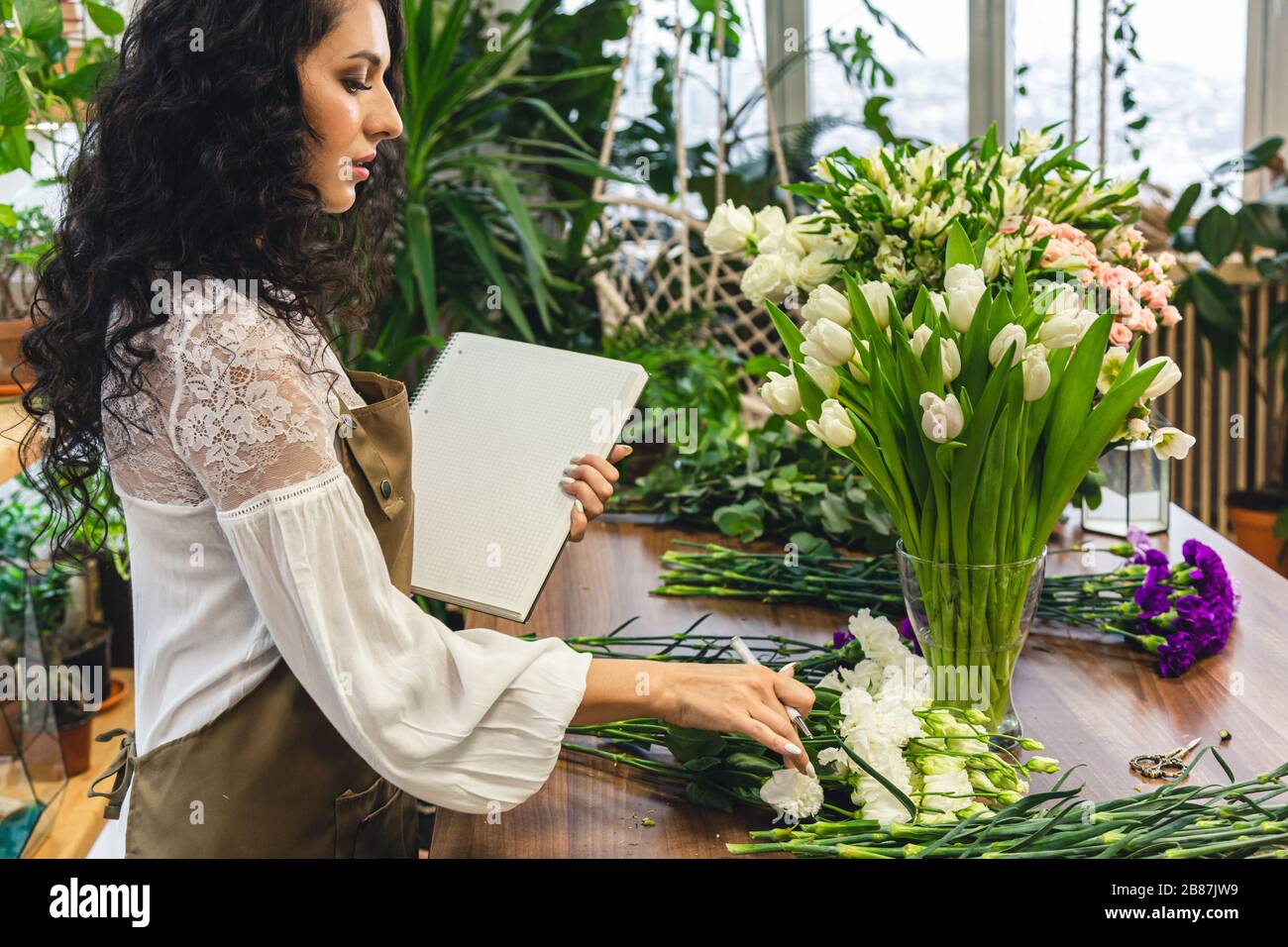 Attractive young woman florist is working in a flower shop Stock Photo ...