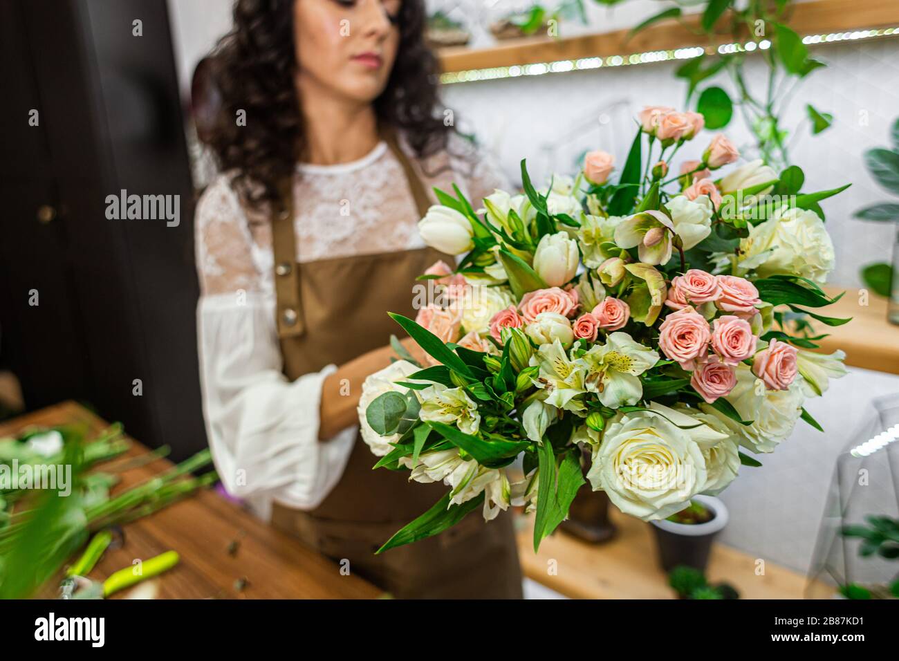 Attractive young woman florist is working in a flower shop Stock Photo ...