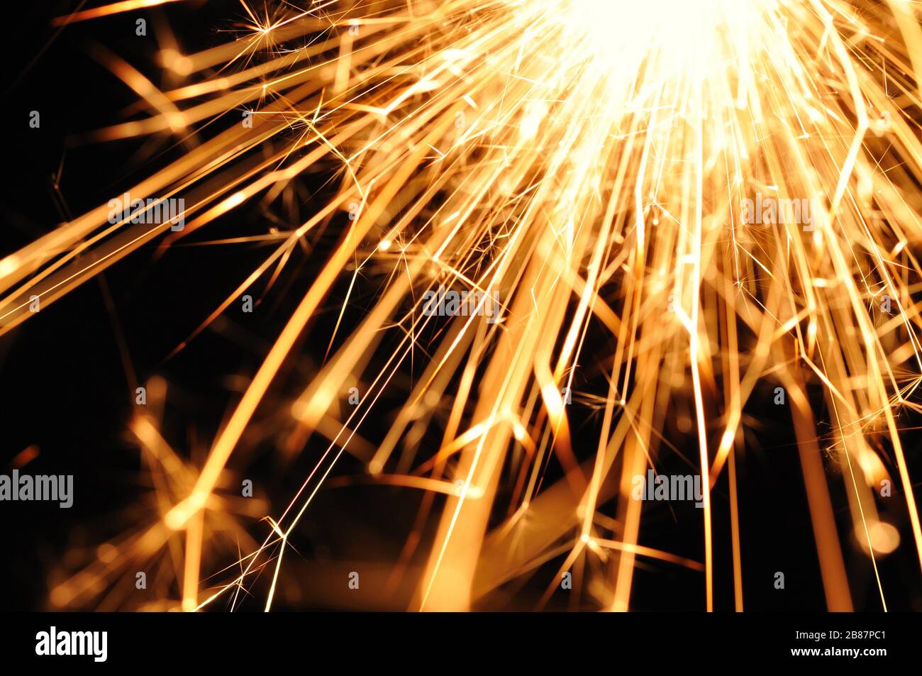 Close-up of golden sparkles of a burning fire on a black background in ...