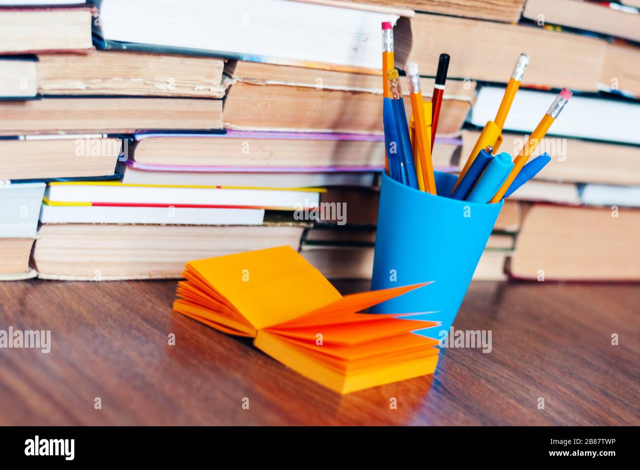 Pencils in holder, note paper and stack of books, school background for ...