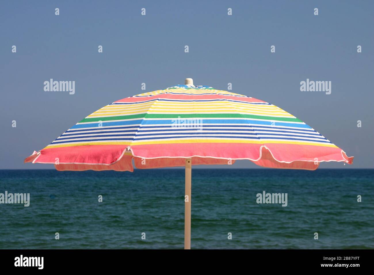 The multi colored beach umbrella shields the sun Stock Photo - Alamy