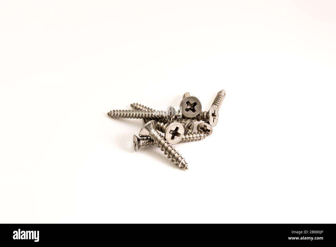 Pile of metal Phillips screws on a background on white Stock Photo - Alamy