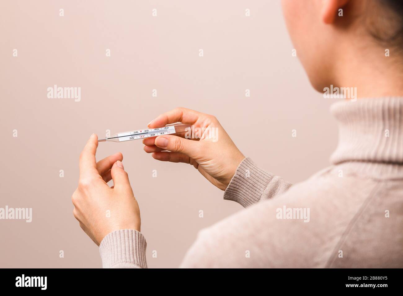 closeup woman hands holding a glass thermometer with high temperature ...