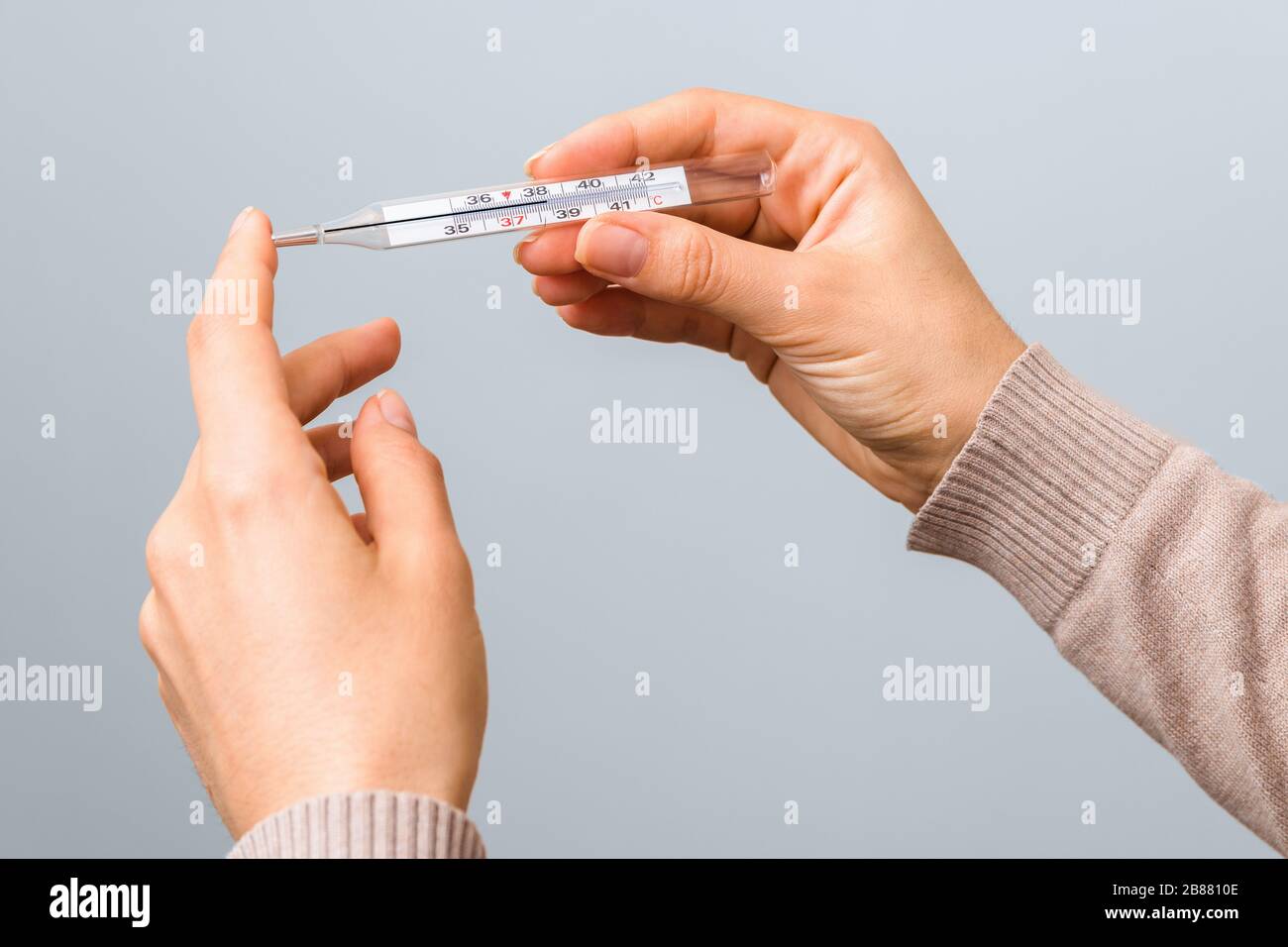 closeup woman hands holding a glass thermometer with high temperature ...