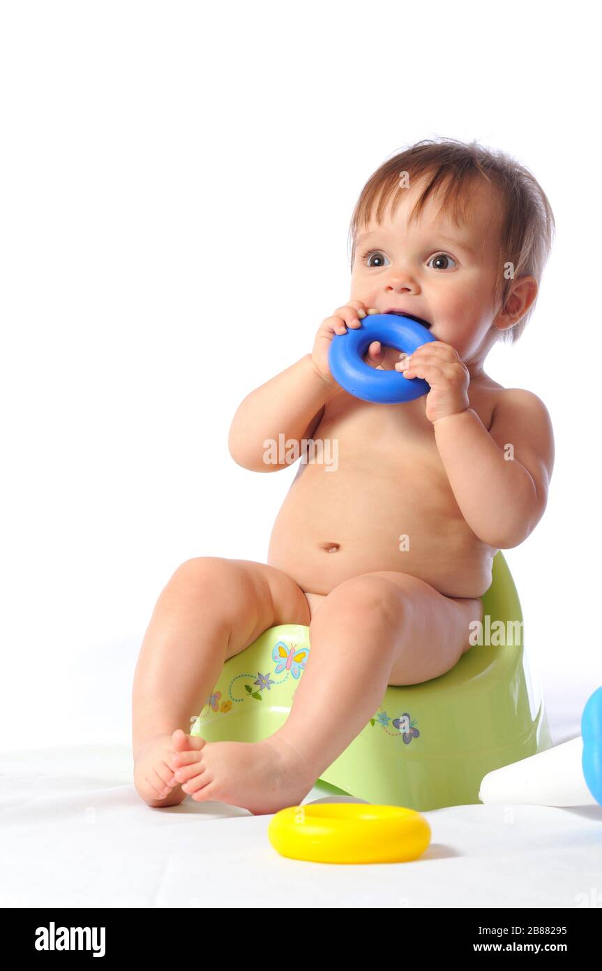 Pretty little baby sits on green potty and plays loved toy. Happy ...