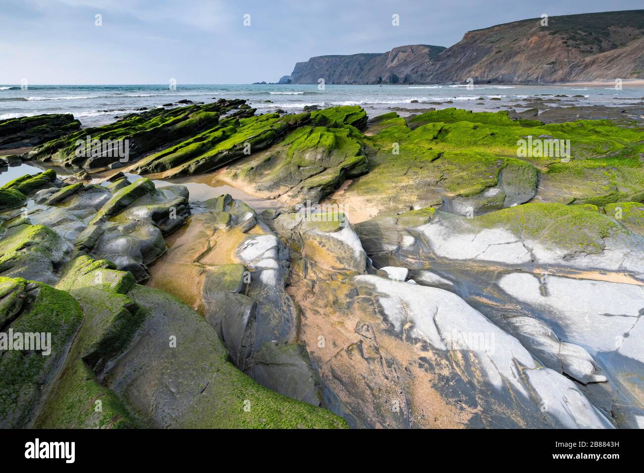 Green overgrown diagonally layered stones on the atlantic coast hi-res ...