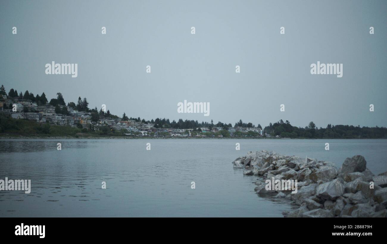 Large strip of rocks near a tree-lined city by the ocean in british ...