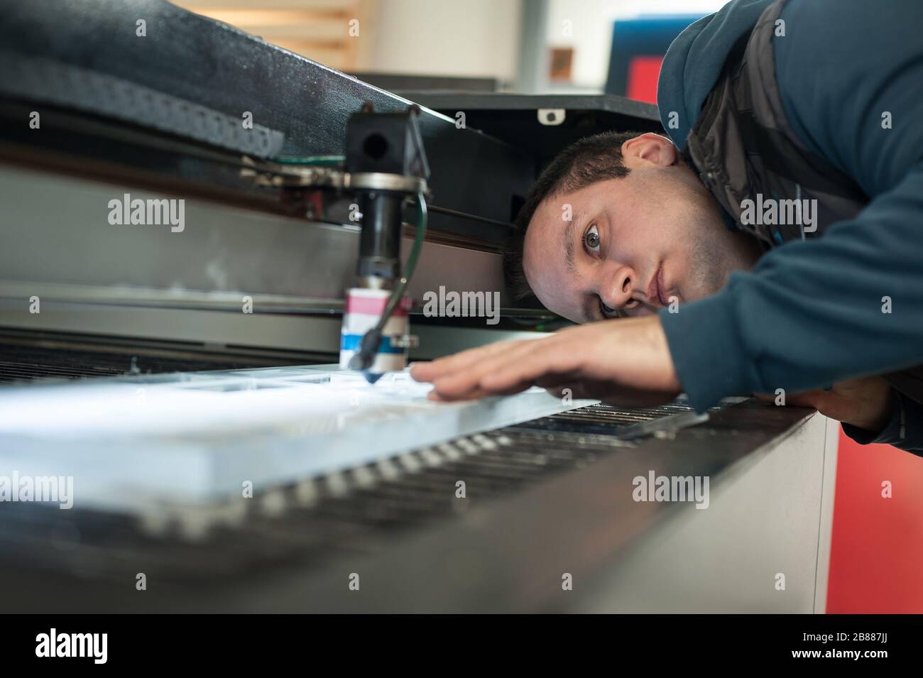 Electrical engineer repairs a laser cutting head on large CNC computer ...