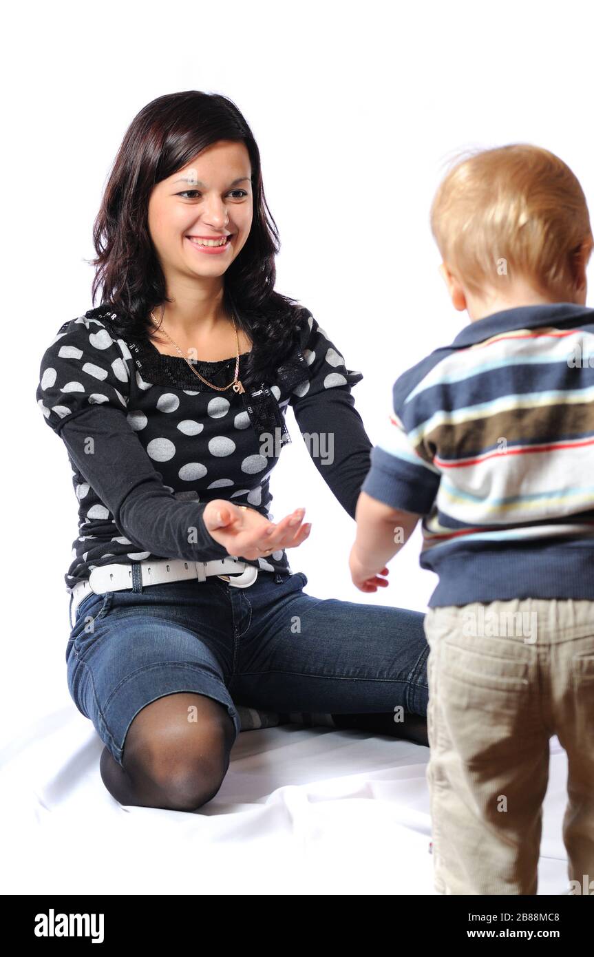 Family portrait of loving mother with her cute little son. Hugging woman sits near standing ...