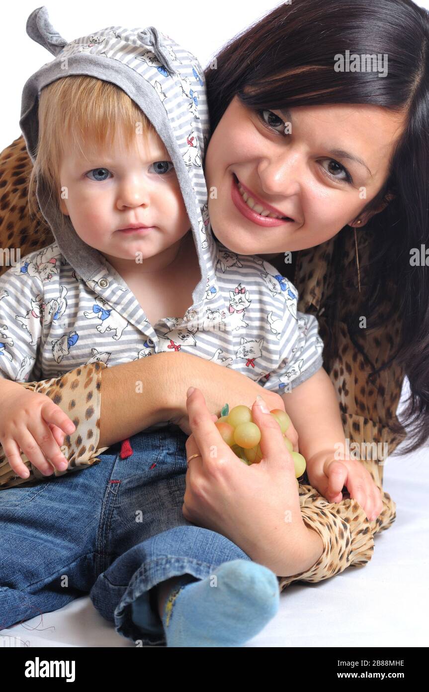 Family portrait of loving mother with her cute little son. Hugging woman sits near standing ...