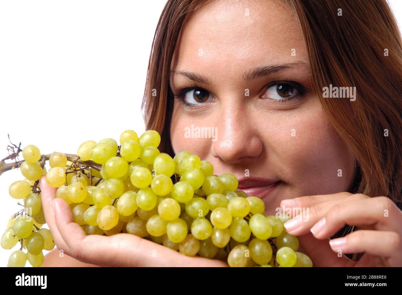 The face of a young girl close-up, a bunch of ripe green grapes. The concept of healthy eating ...