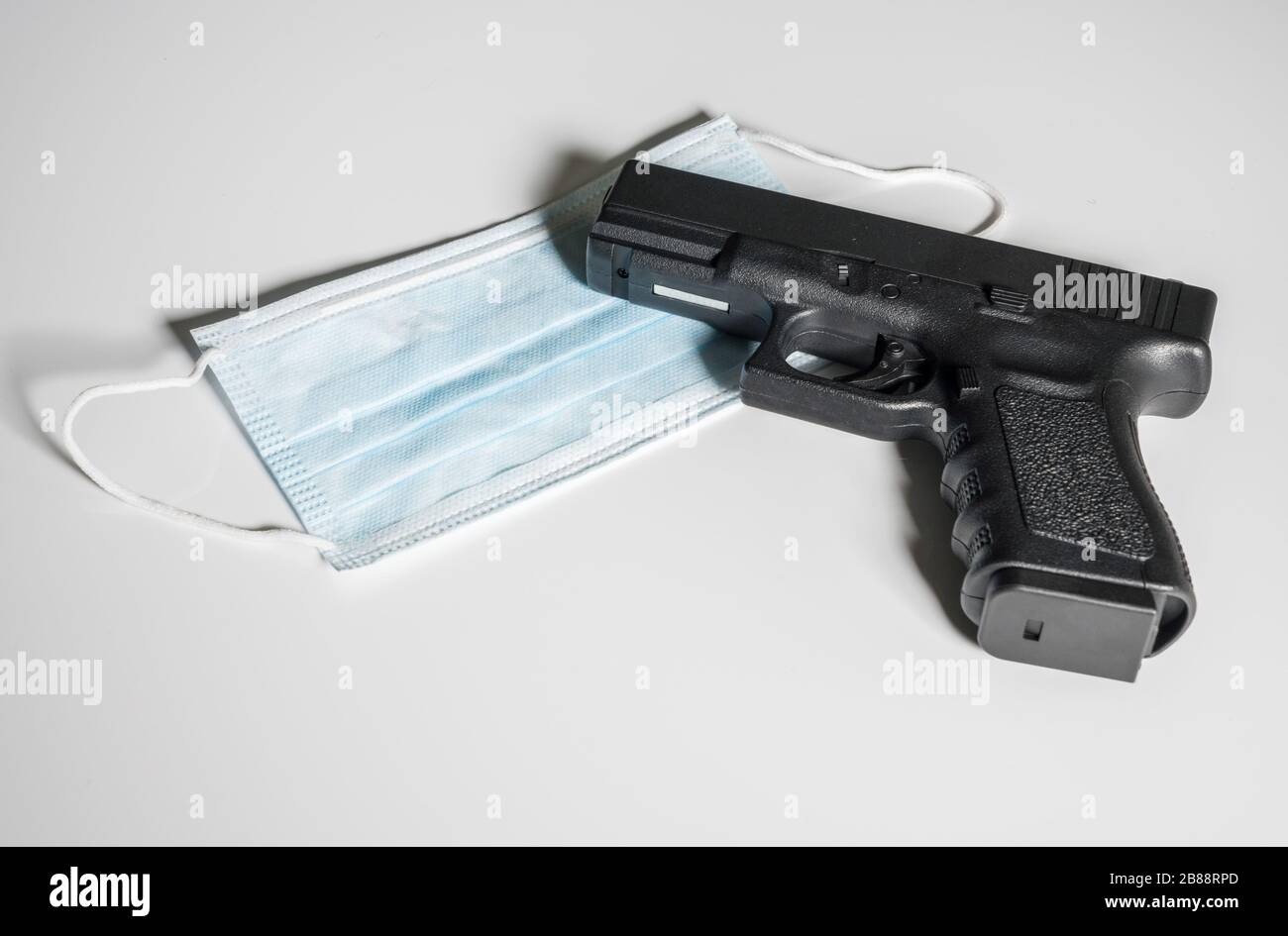 Pistol gun laying on top of medical mask in concept for dangers faced ...
