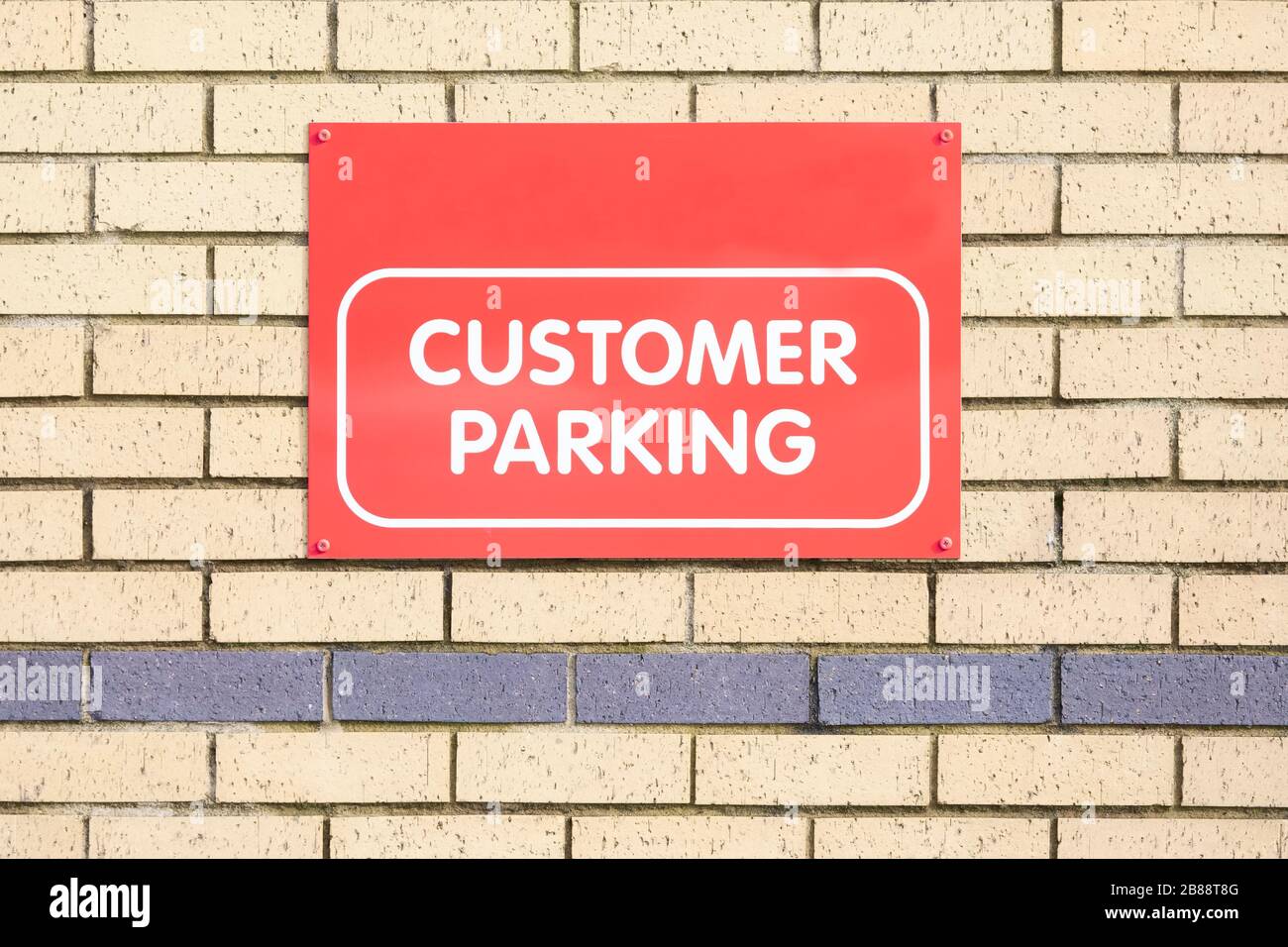 Customer parking only sign on brick wall at bank shop car park Stock ...
