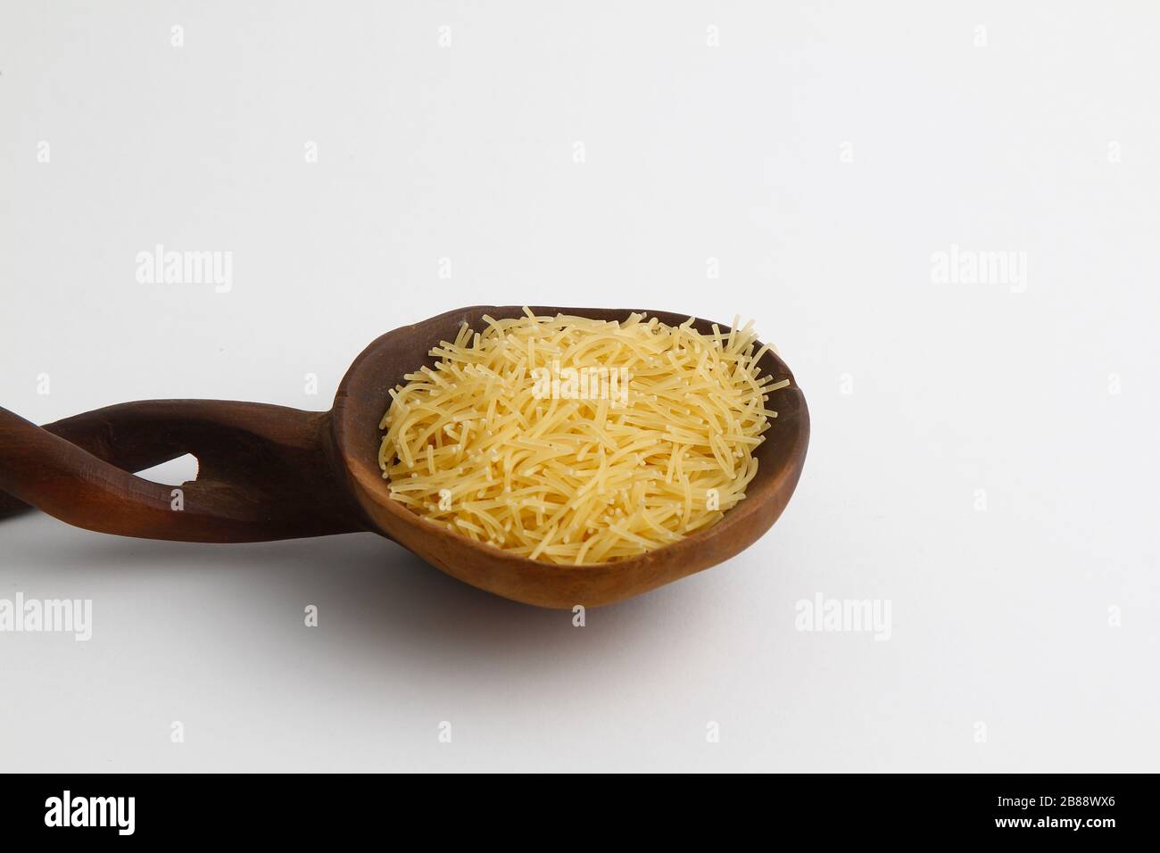 Small noodles on a wooden spoon and scattering. White background Stock ...