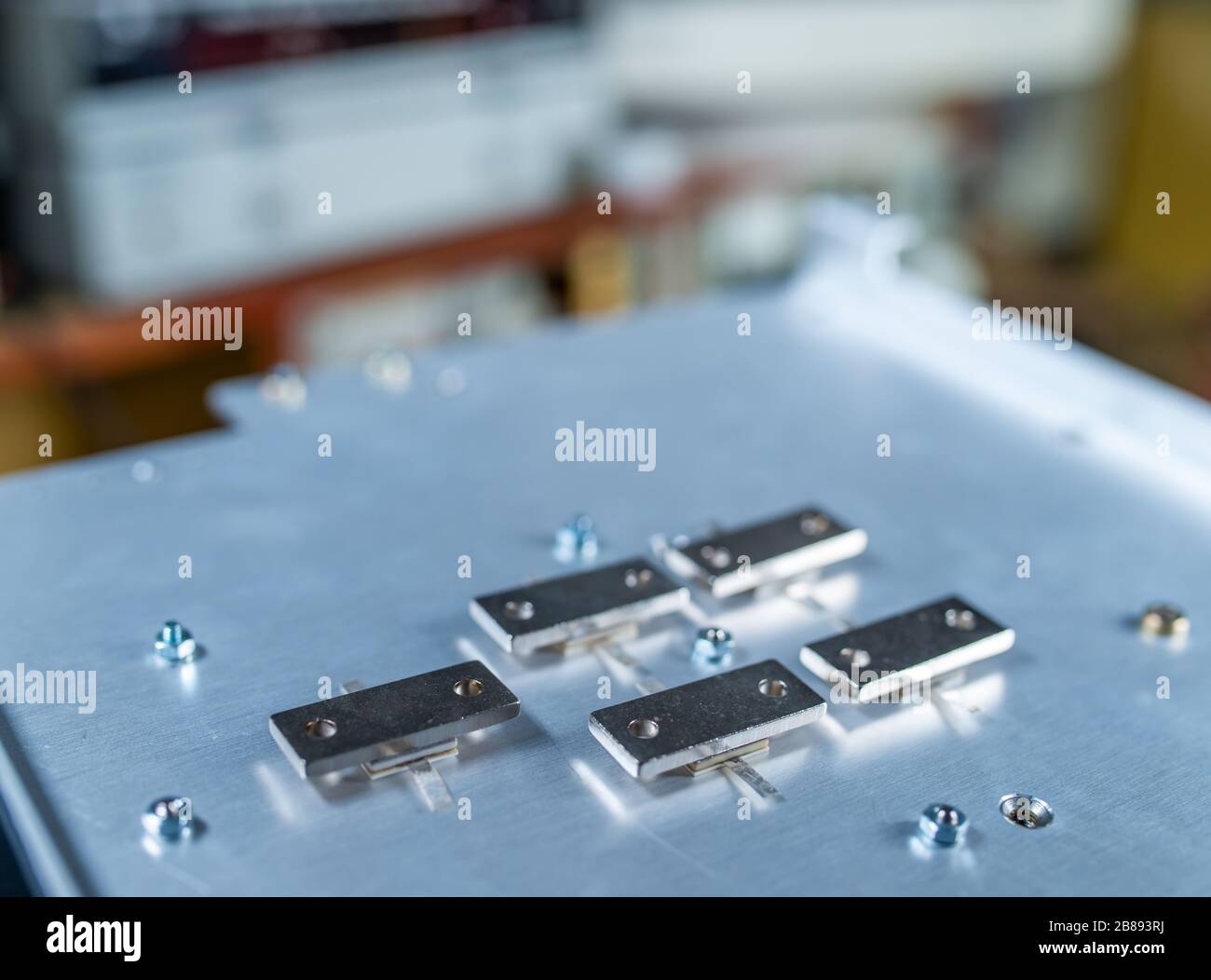 Close-up of five metal plates screwed to a large iron platform. Concept ...