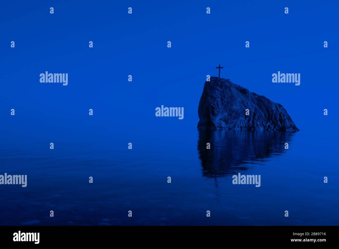 Sea rock with cross on top and seaweed and break on them at night in ...