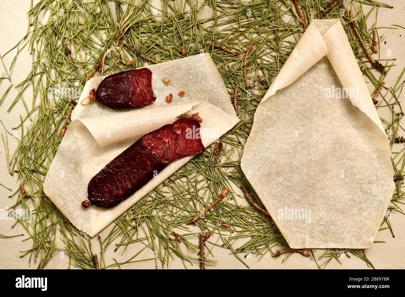 Dried sausage made of roe meat on parchment left and right with a ...