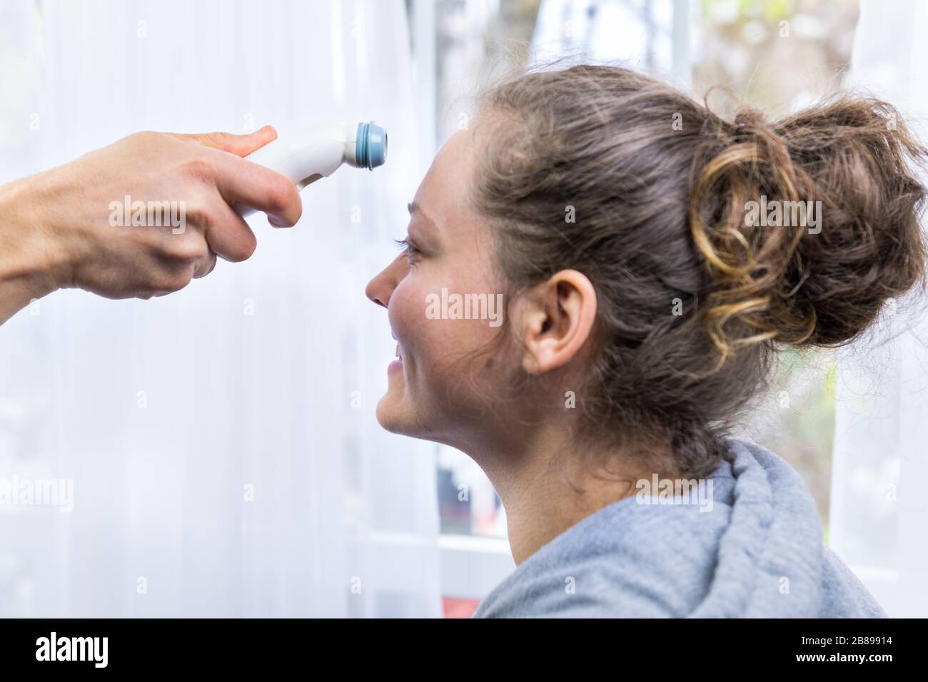 Doctor in white medical coat measuring temperature from young smiling ...