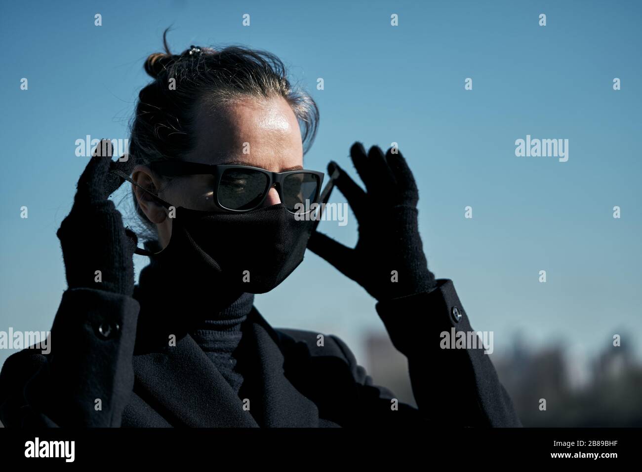 Young girl in a black protective mask and black sunglasses on the ...
