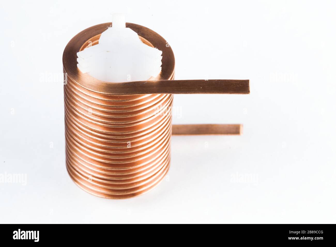 Close-up flat twisted copper wire on a plastic bung on a white surface ...