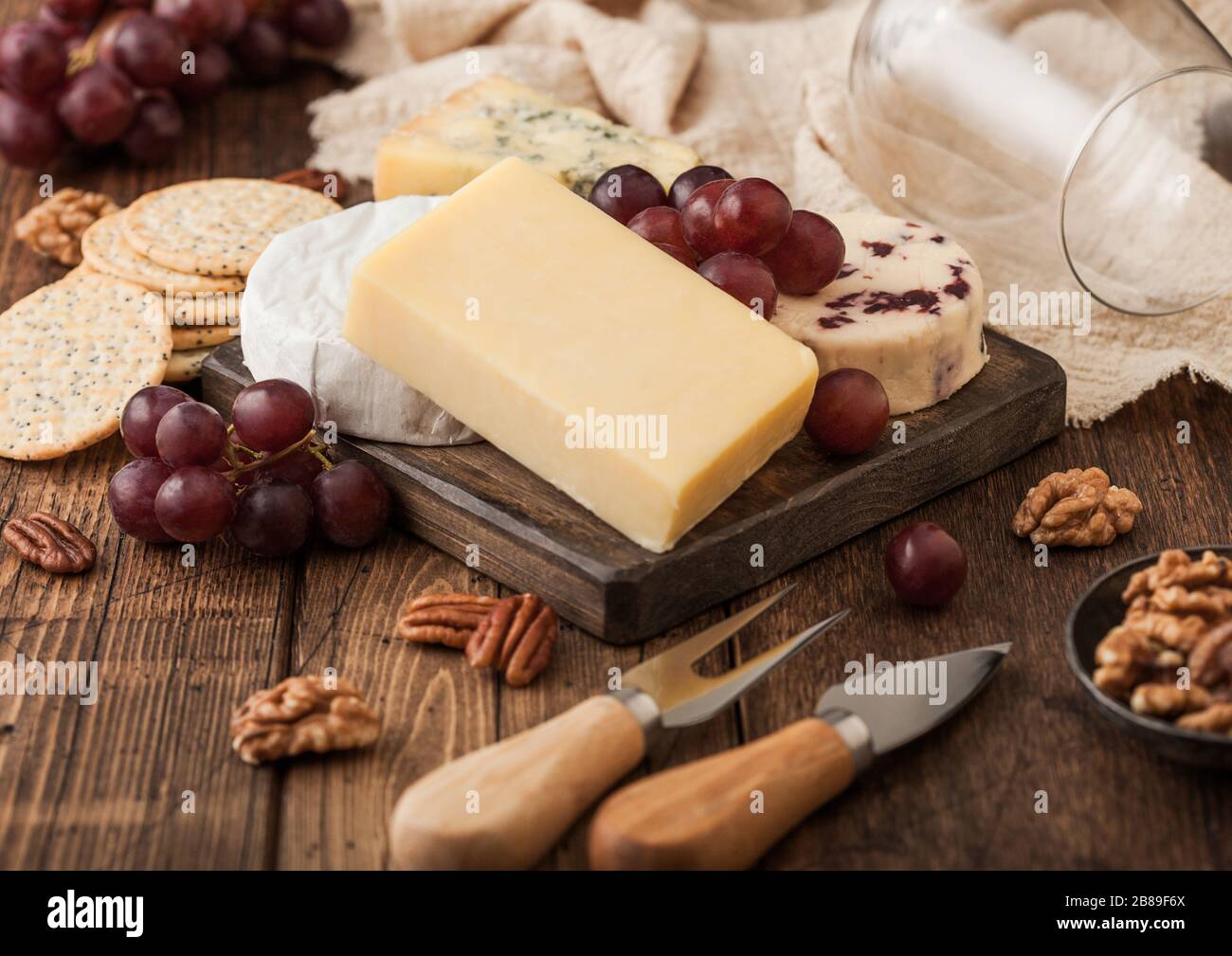 Selection of various cheese on the board and grapes on wooden table ...