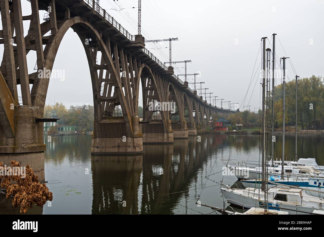 Arched railroad bridge crosses a river on foggy fall day Stock Photo ...