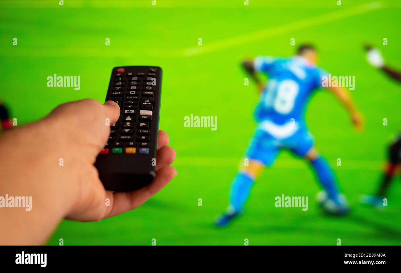 Hand catching a tv remote control with the tv with football. Soccer and ...