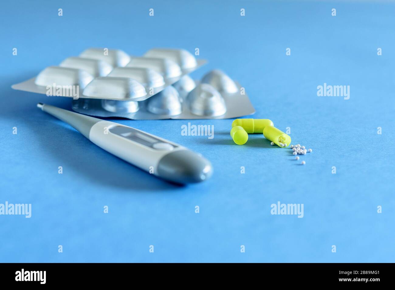Anti flu capsule tablets and thermometer closeup on the blue background ...