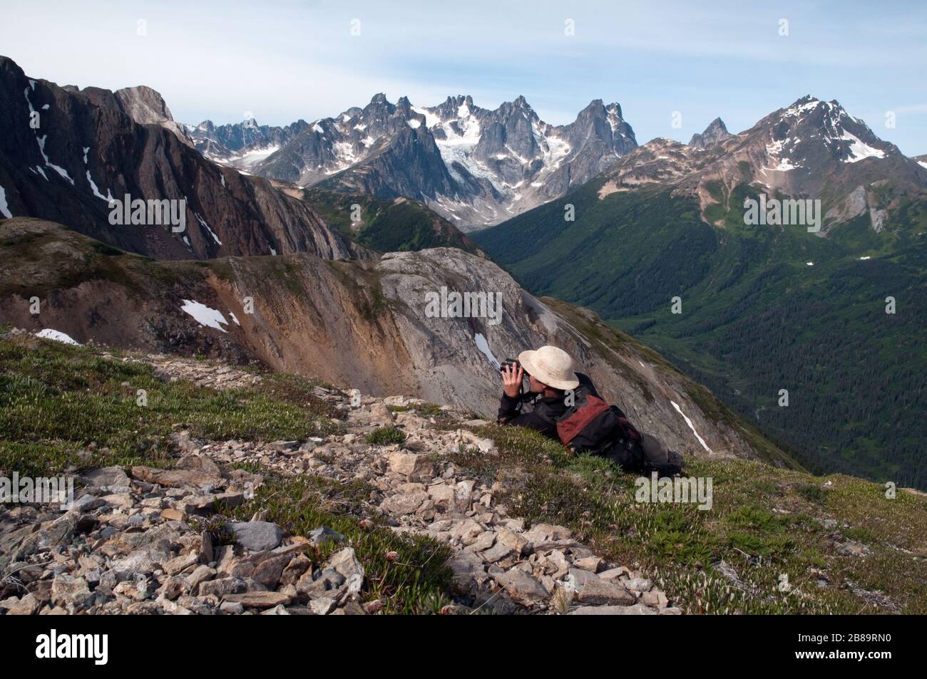 A solo hiker looking through binoculars in the Boundary Ranges of the ...