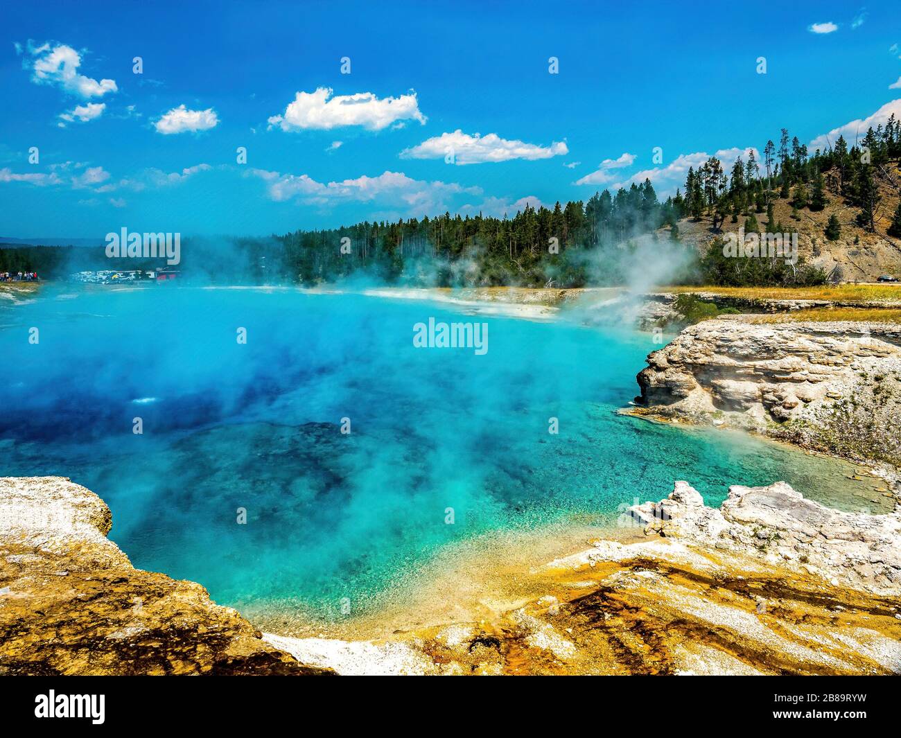 blue hot springs in Yellowstone National Park on a sunny day with mist ...
