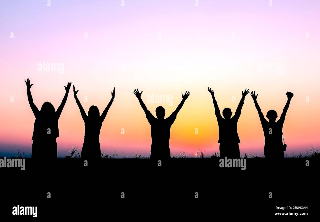 Silhouette group of people raising hands up at sunset moment with ...