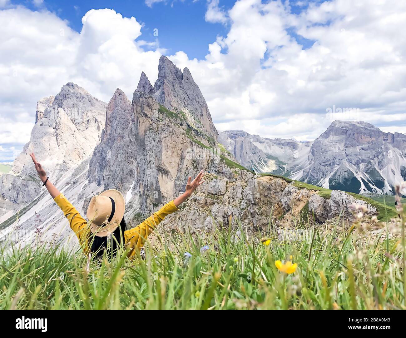 Female traveler raising hands up, enjoying scenery of Seceda mountain ...