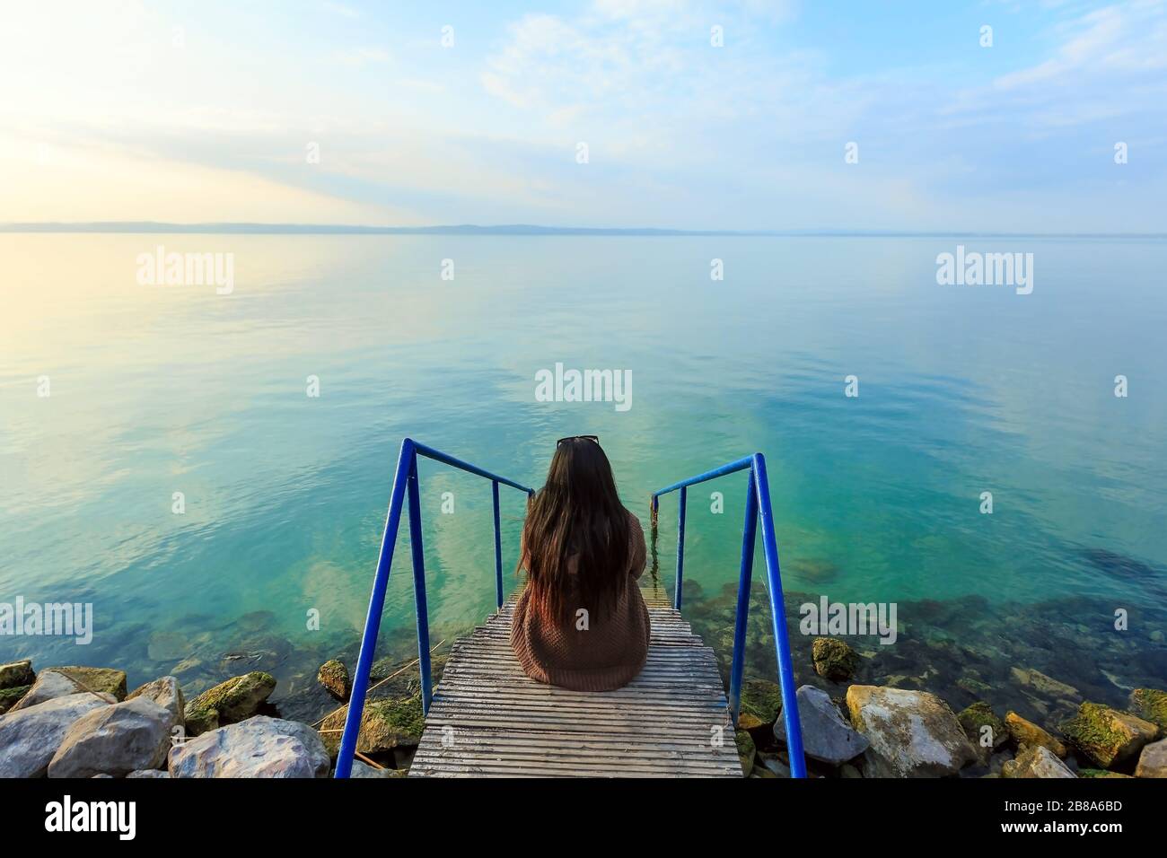 Back of woman sitting by lakeside of Balaton lake, Hungary Stock Photo ...