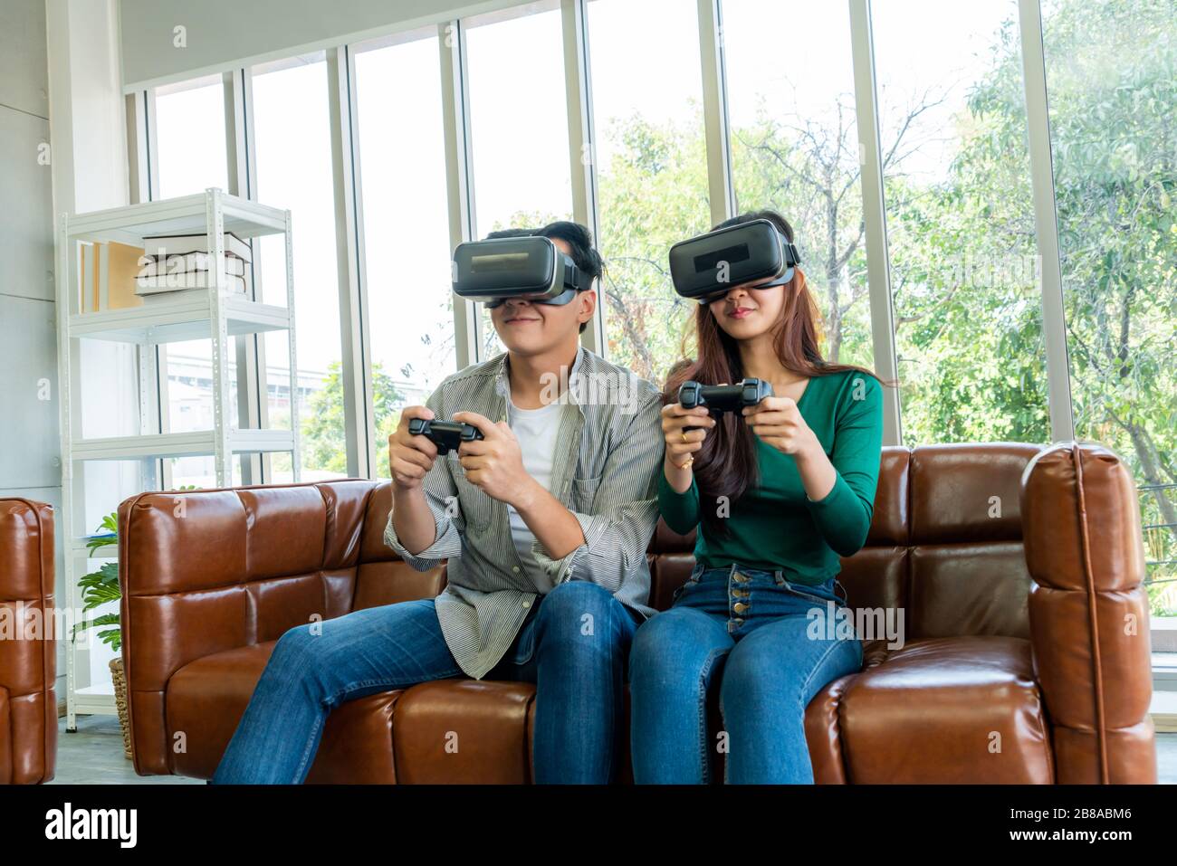 Young happy Asian couple playing video games in living room. Cheerful ...