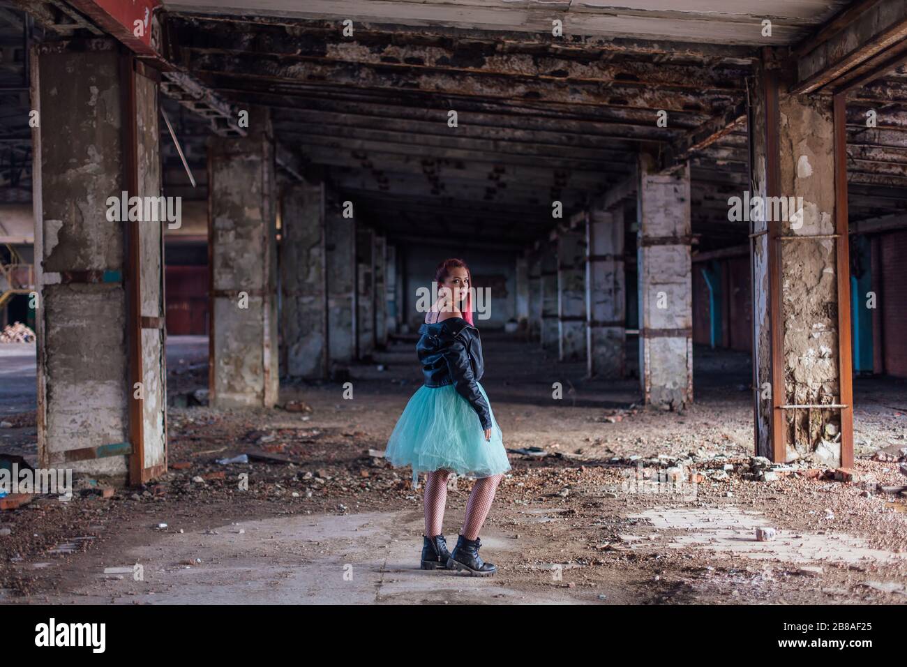 Portrait of a young girl with pink hair standing inside of collapsed ...