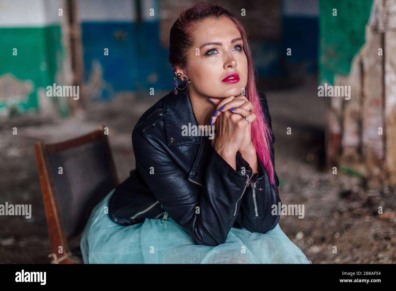 Portrait of a young girl with pink hair sitting old the old chair ...