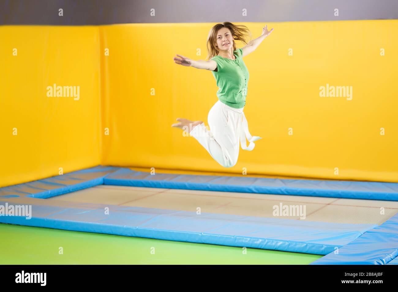 Young woman jumping and bouncing on a trampoline in sport center Stock ...
