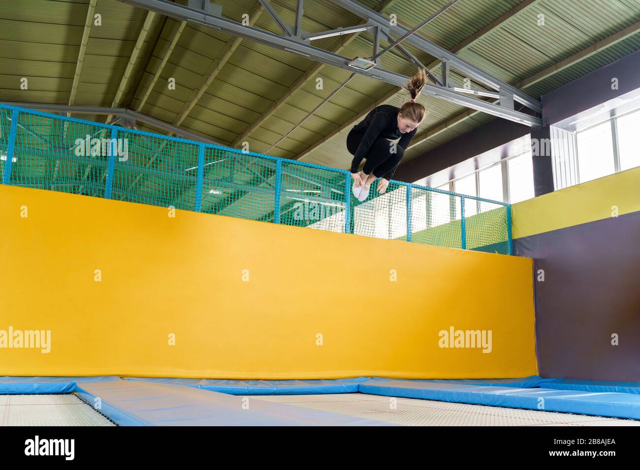Young woman amateur acrobatic athlete jumping and exercising on a ...