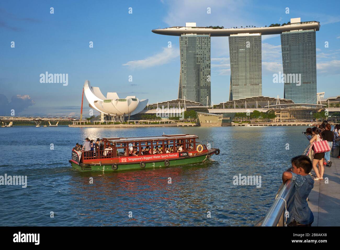 An excursion boat riding across Marina Bay, the iconic Marina Bay Sands ...