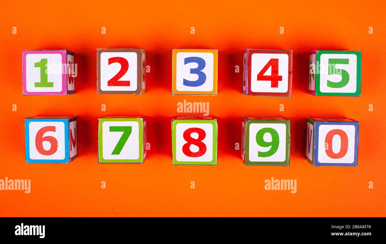 wooden cubes with numbers exactly stacked on an orange background top ...