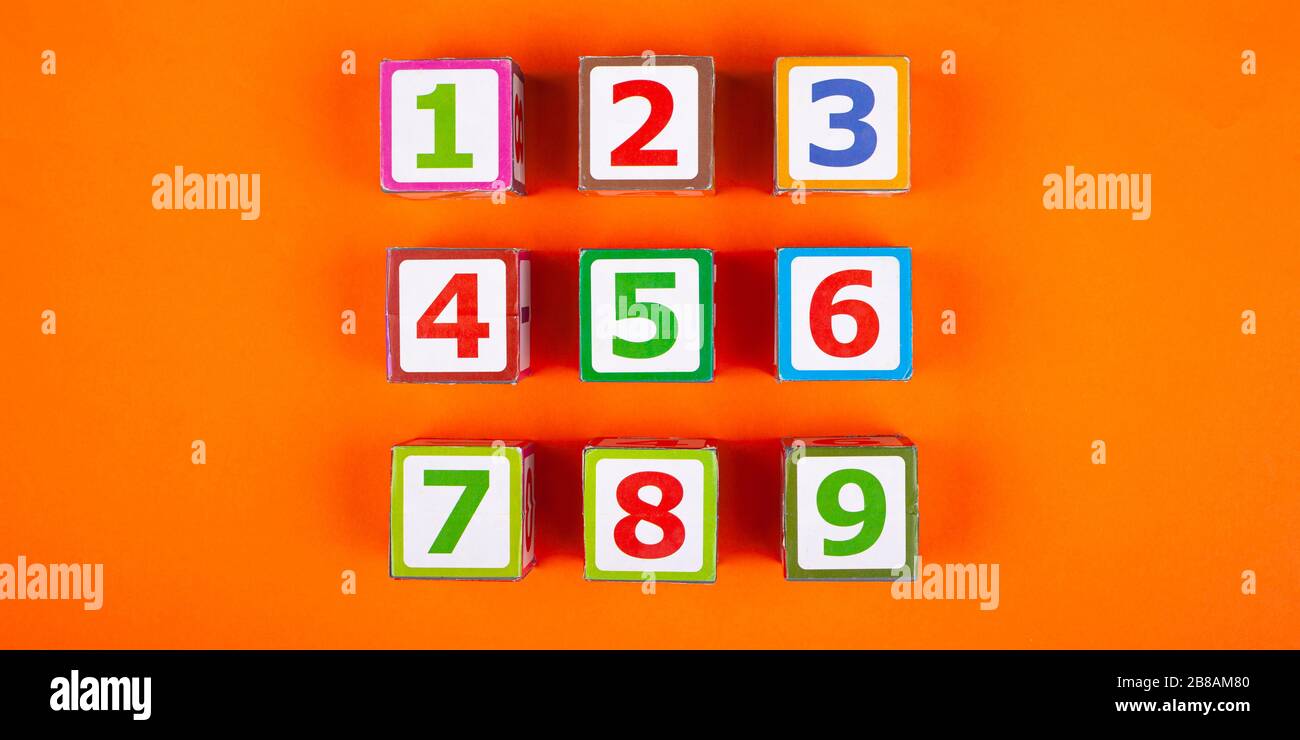 wooden cubes with numbers exactly stacked on an orange background top ...