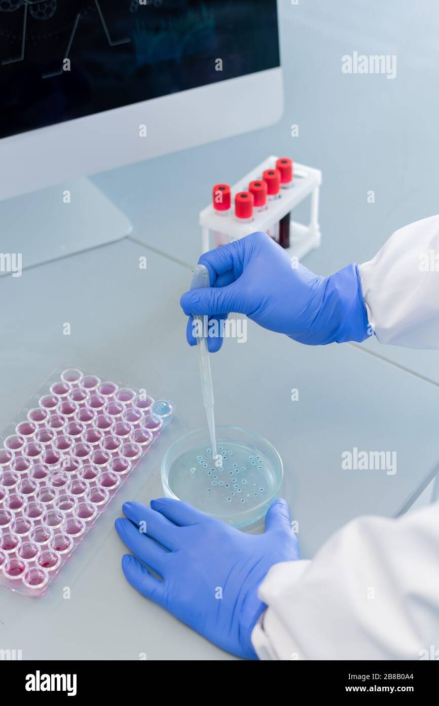 Gloved hands of contemporary pharmacist with pipette putting new ...