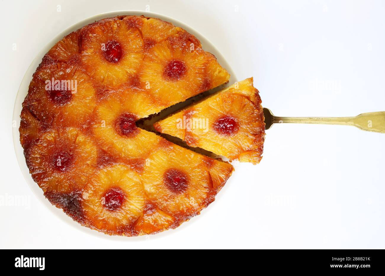 Cutted Pineapple upside down cake with glacé cherry and scapula on ...